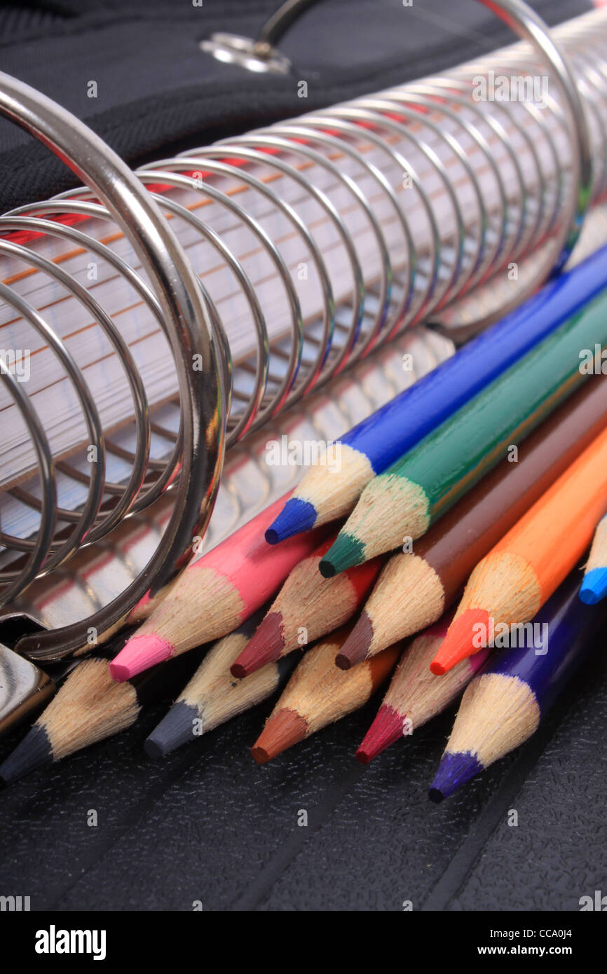 Colorful sharpened pencil crayons for school beside three ring binder ...