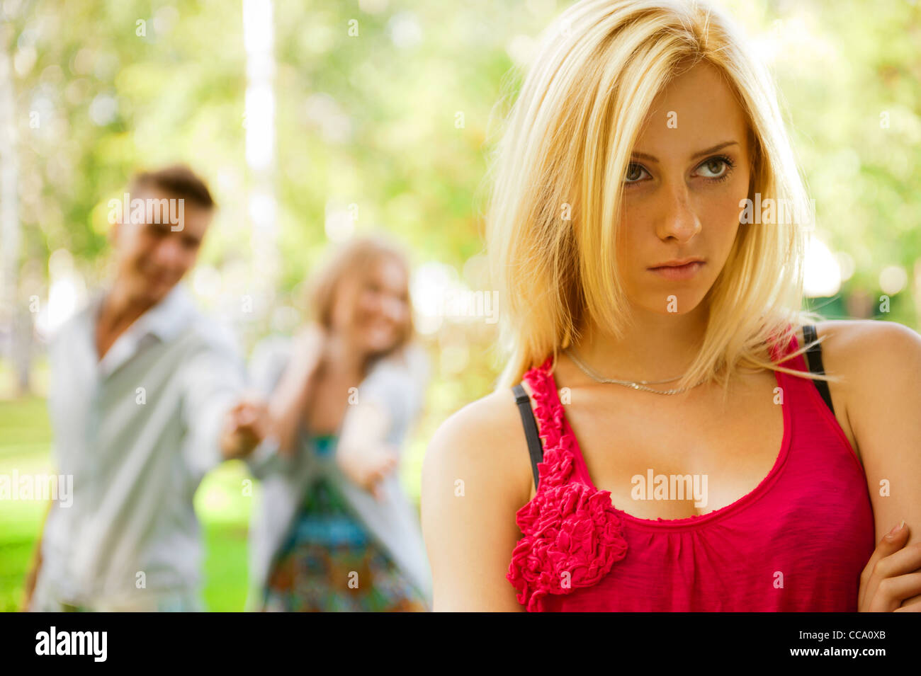 Upset teenage girl being jeered by group of the other young people ...