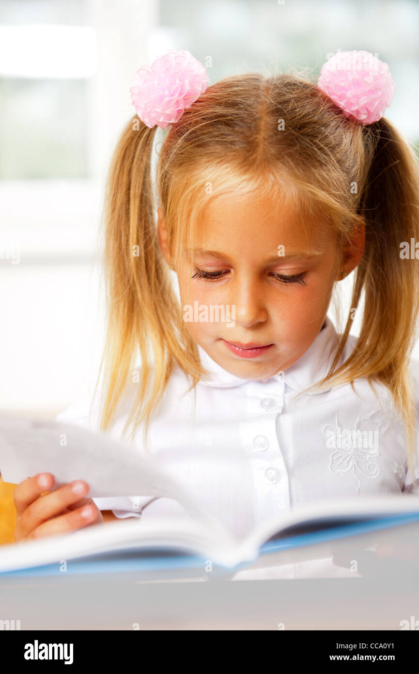 Image of smart child reading interesting book in classroom. Vertical ...