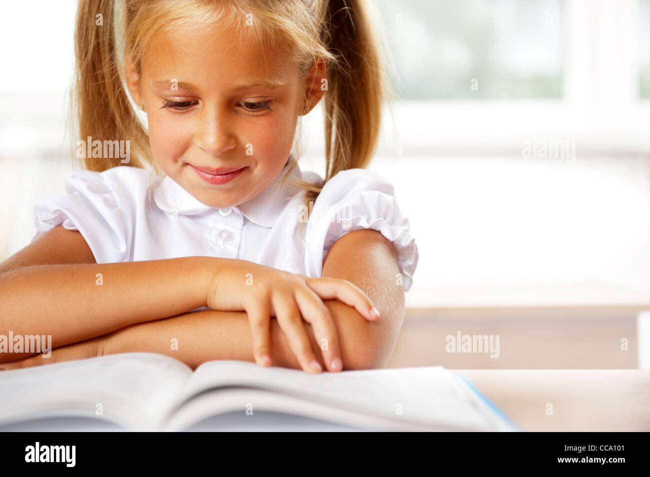 Image of smart child reading interesting book in classroom. Horizontal ...