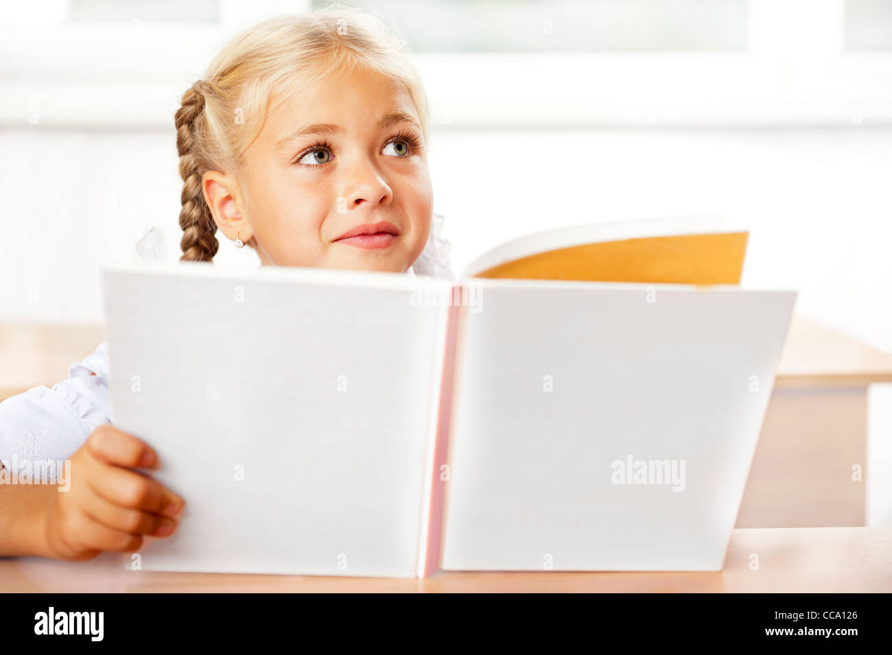 Image of smart child reading interesting book in classroom. Horizontal ...
