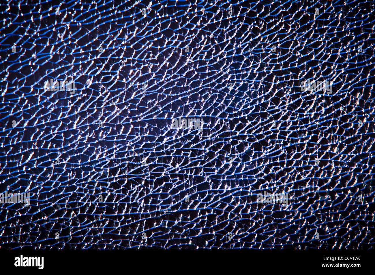 A spider-web of cracks run through a piece of safety glass in a car ...