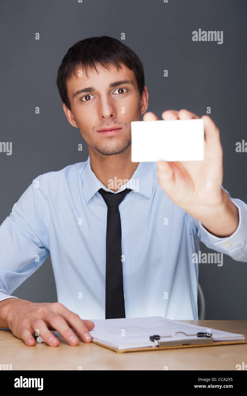 Business man handing a blank business card over grey background Stock ...