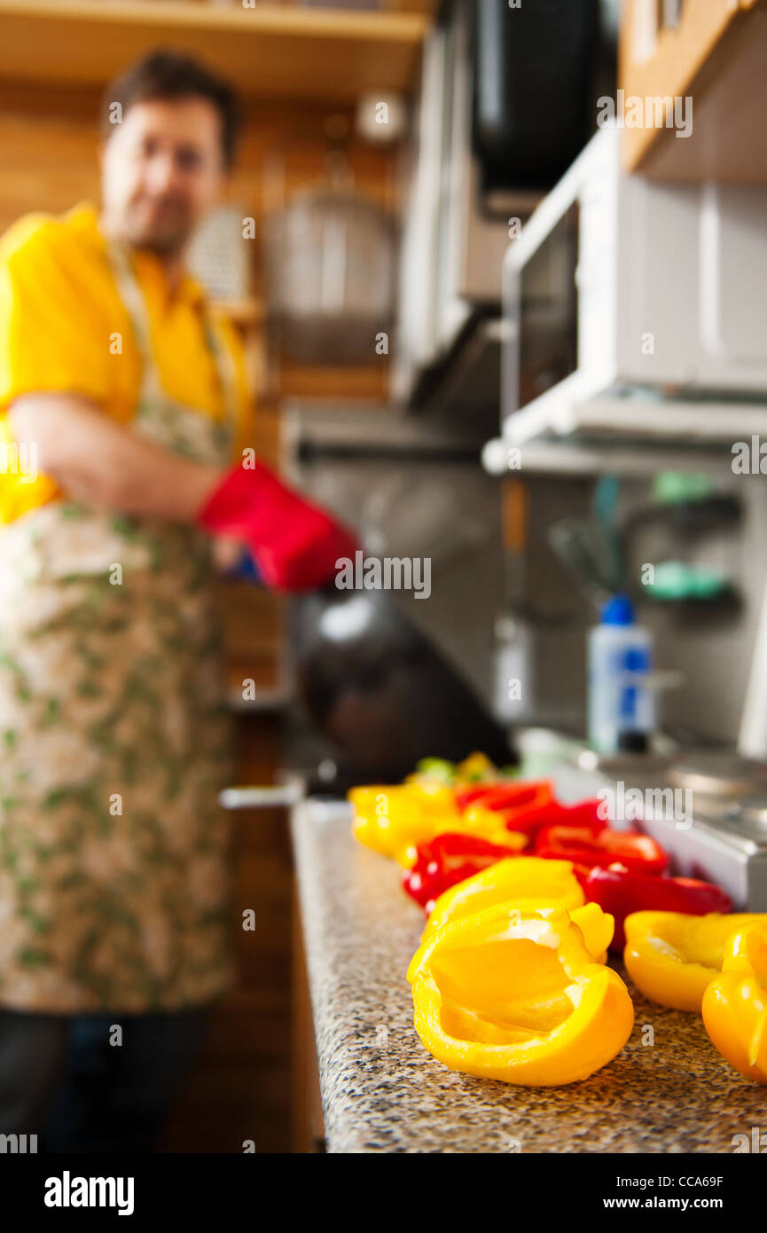 Handsome man cooking in the kitchen at home. man on background. Peppers ...
