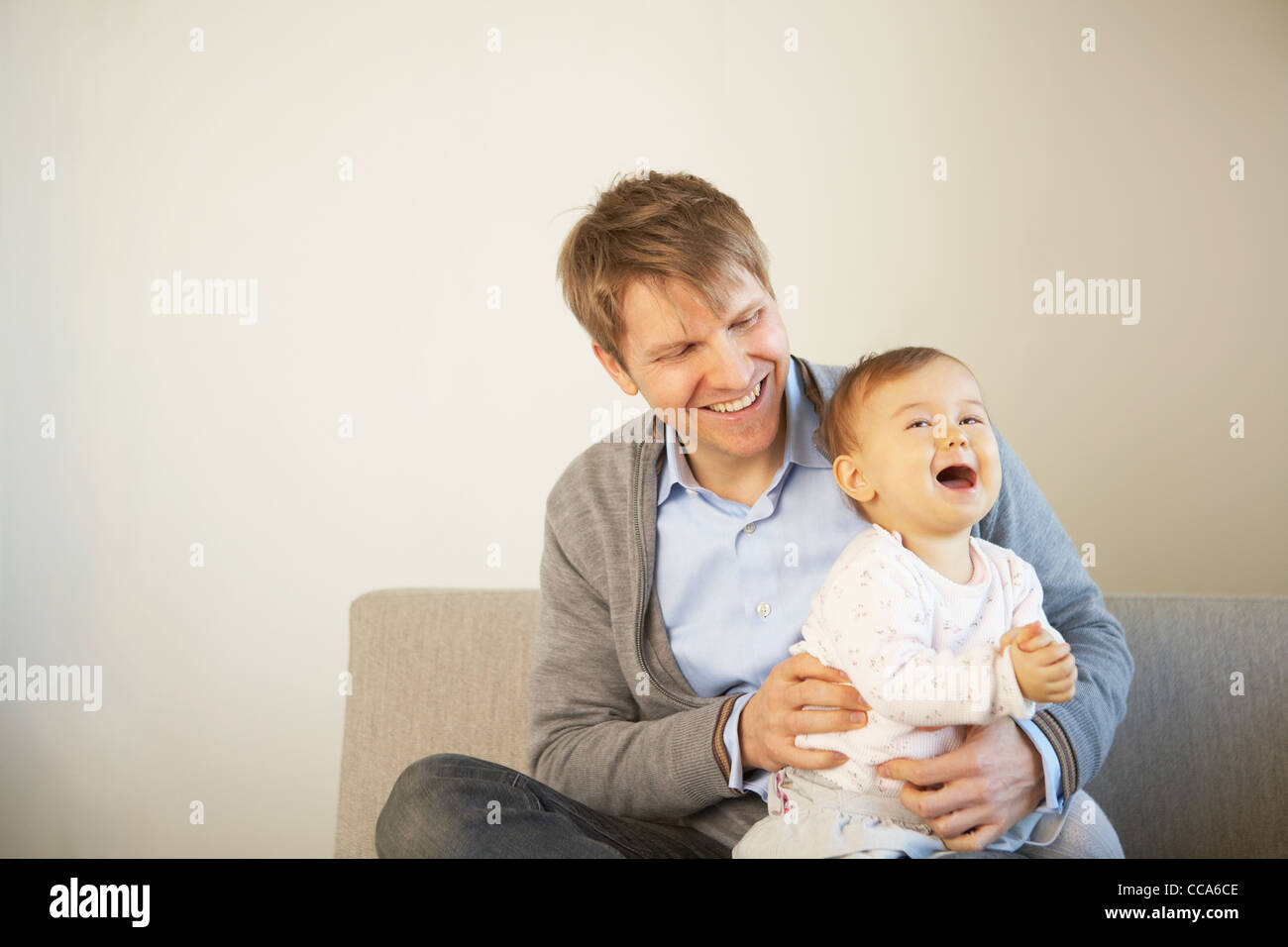 Baby Girl Sitting on Father's Lap Stock Photo - Alamy