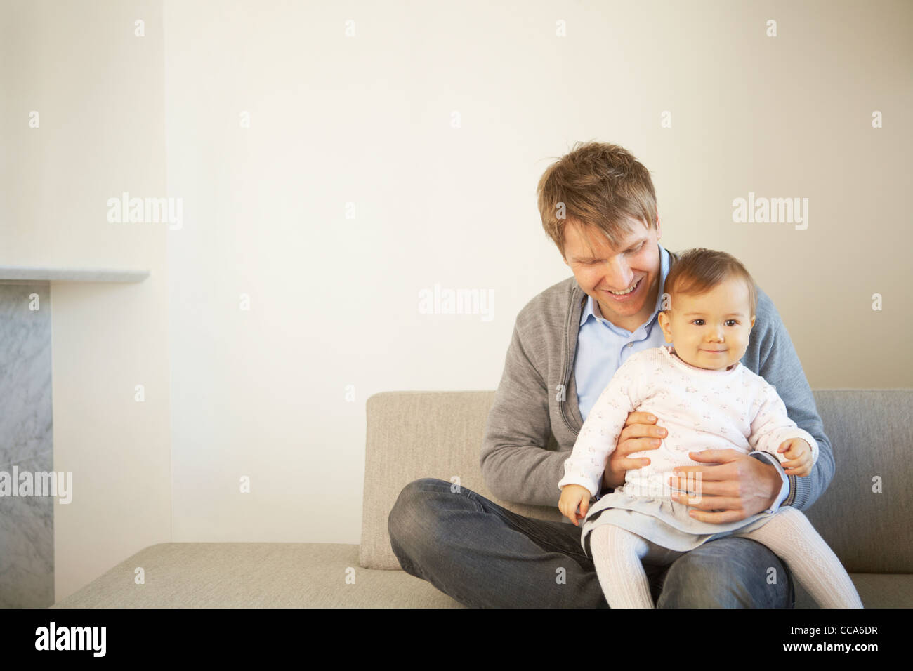 Baby Girl Sitting on Father's Lap Stock Photo - Alamy