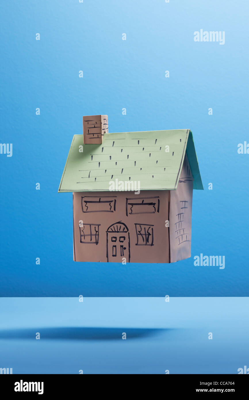 Floating cardboard house against blue background Stock Photo - Alamy