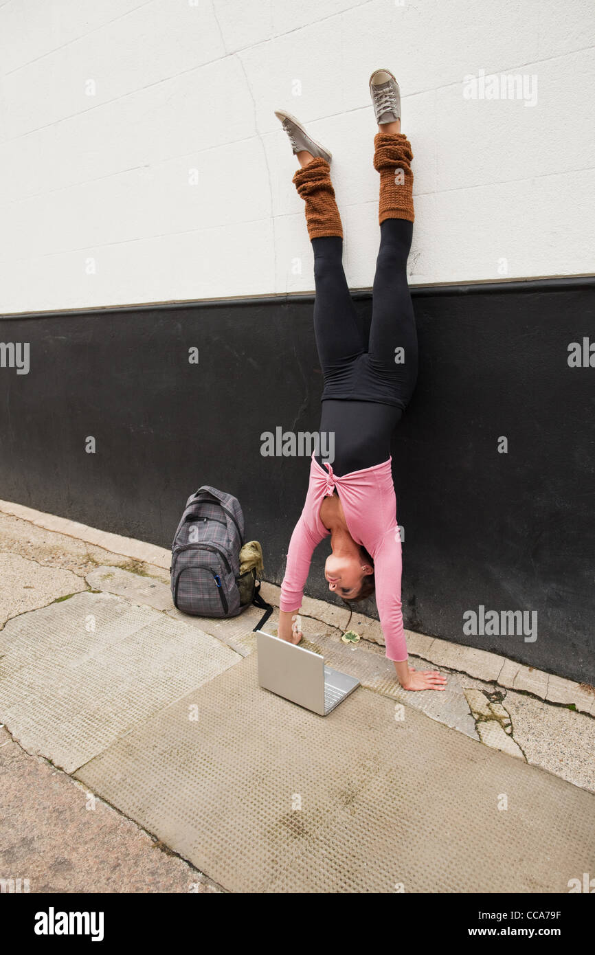 Woman performing handstand and using laptop on pavement Stock Photo - Alamy