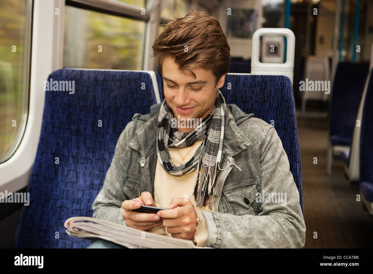 Young man travelling on train using cellphone Stock Photo - Alamy