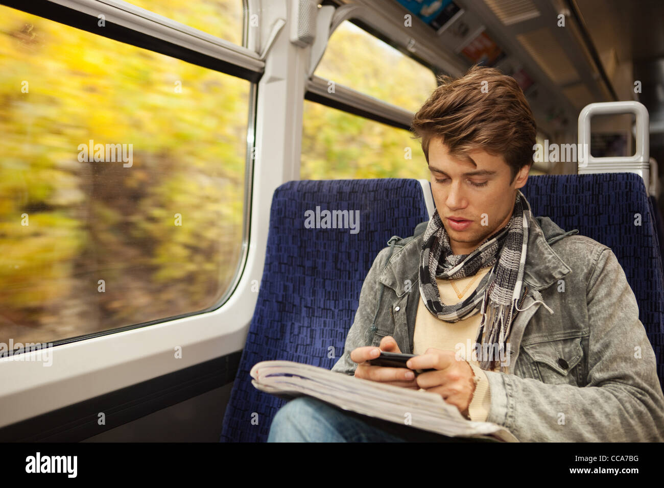 Young man travelling on train using cellphone Stock Photo - Alamy