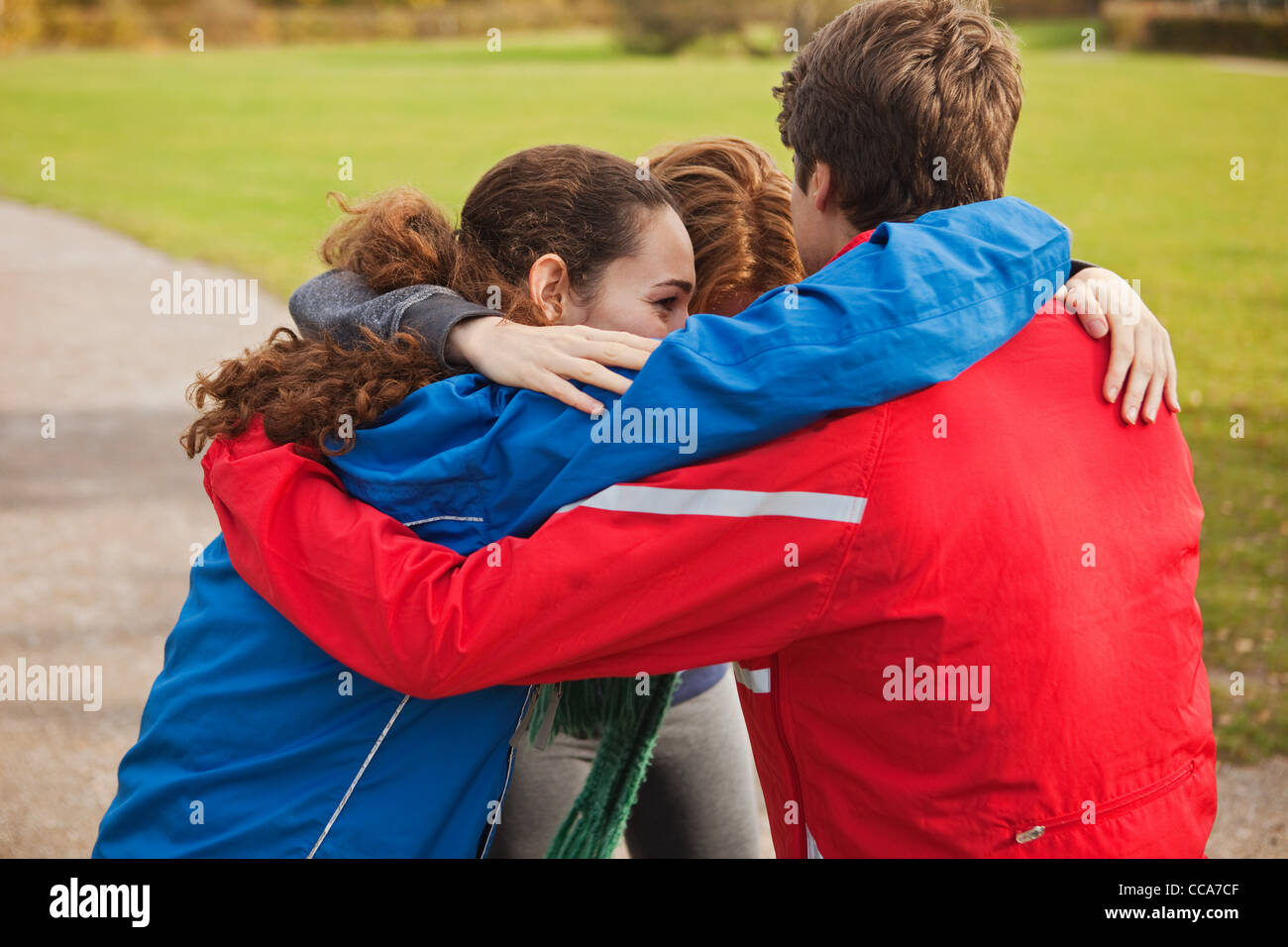 Young friends huddling together in park Stock Photo - Alamy