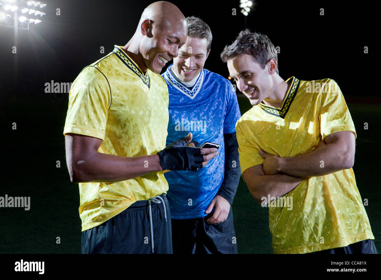 Soccer players looking at cellphone on pitch Stock Photo - Alamy
