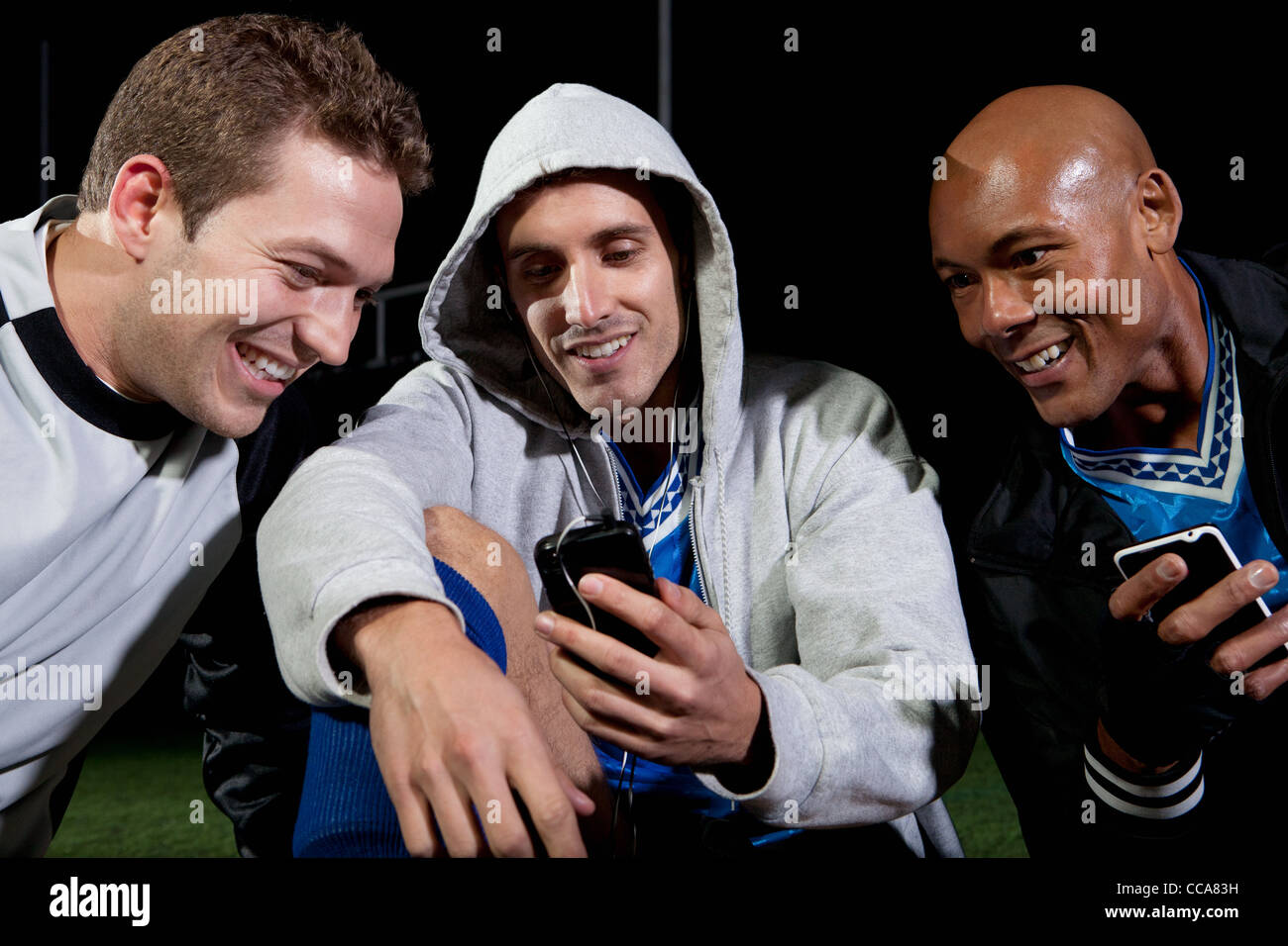 Soccer players looking at cellphone on pitch Stock Photo - Alamy