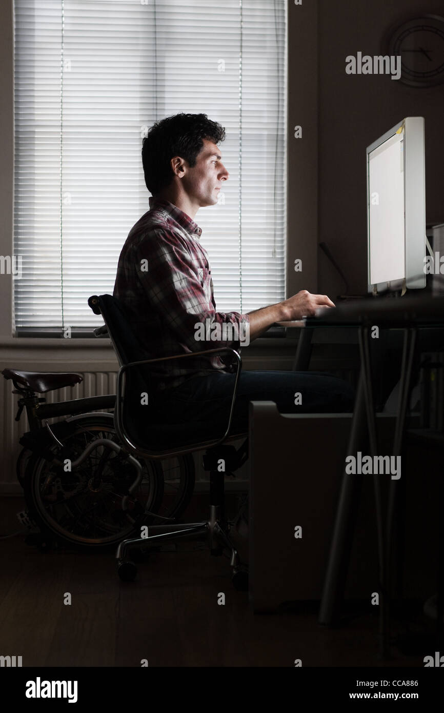 Mid adult man using home computer at desk Stock Photo - Alamy
