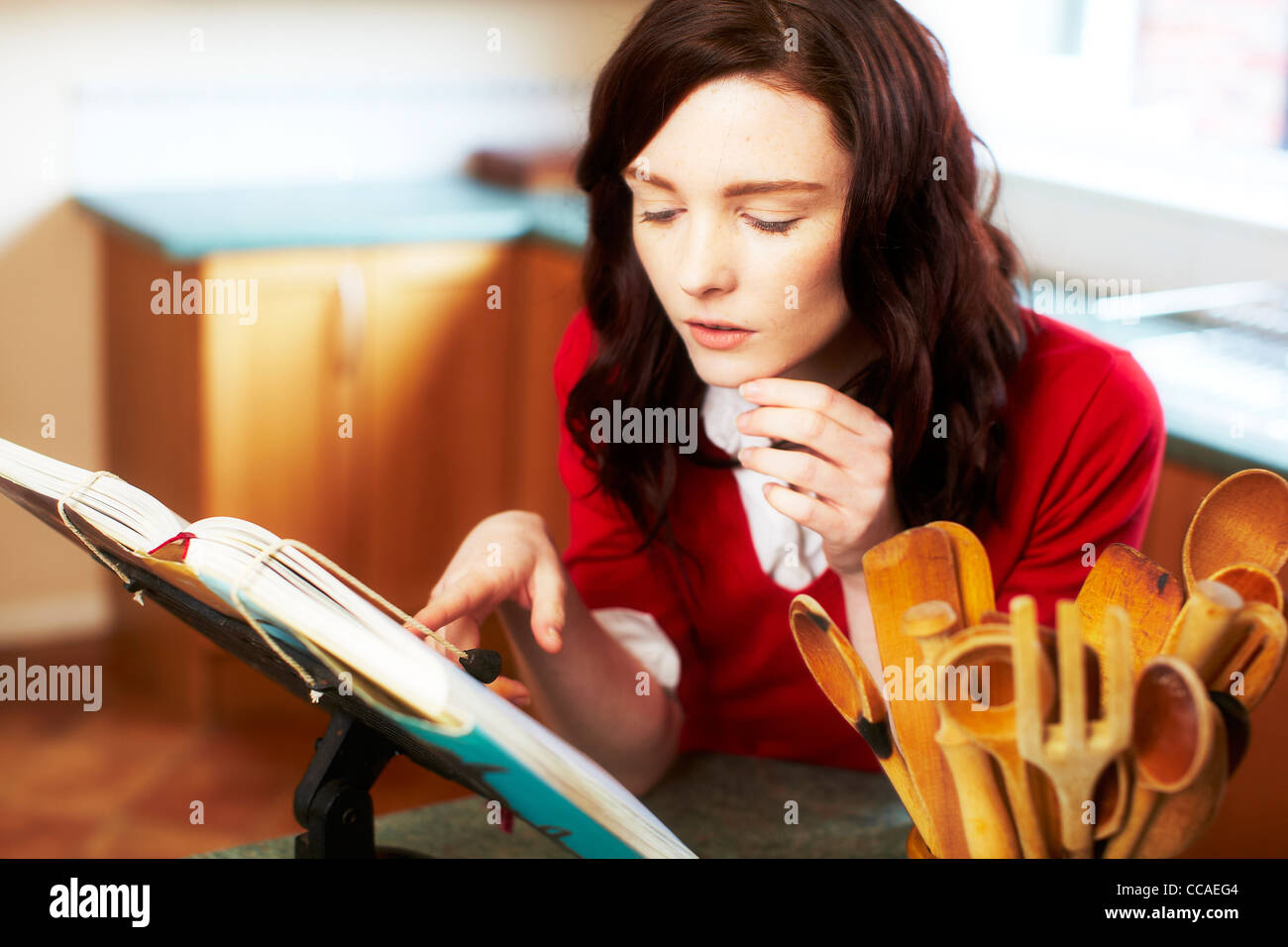 Girl reading cook book in kitchen Stock Photo - Alamy