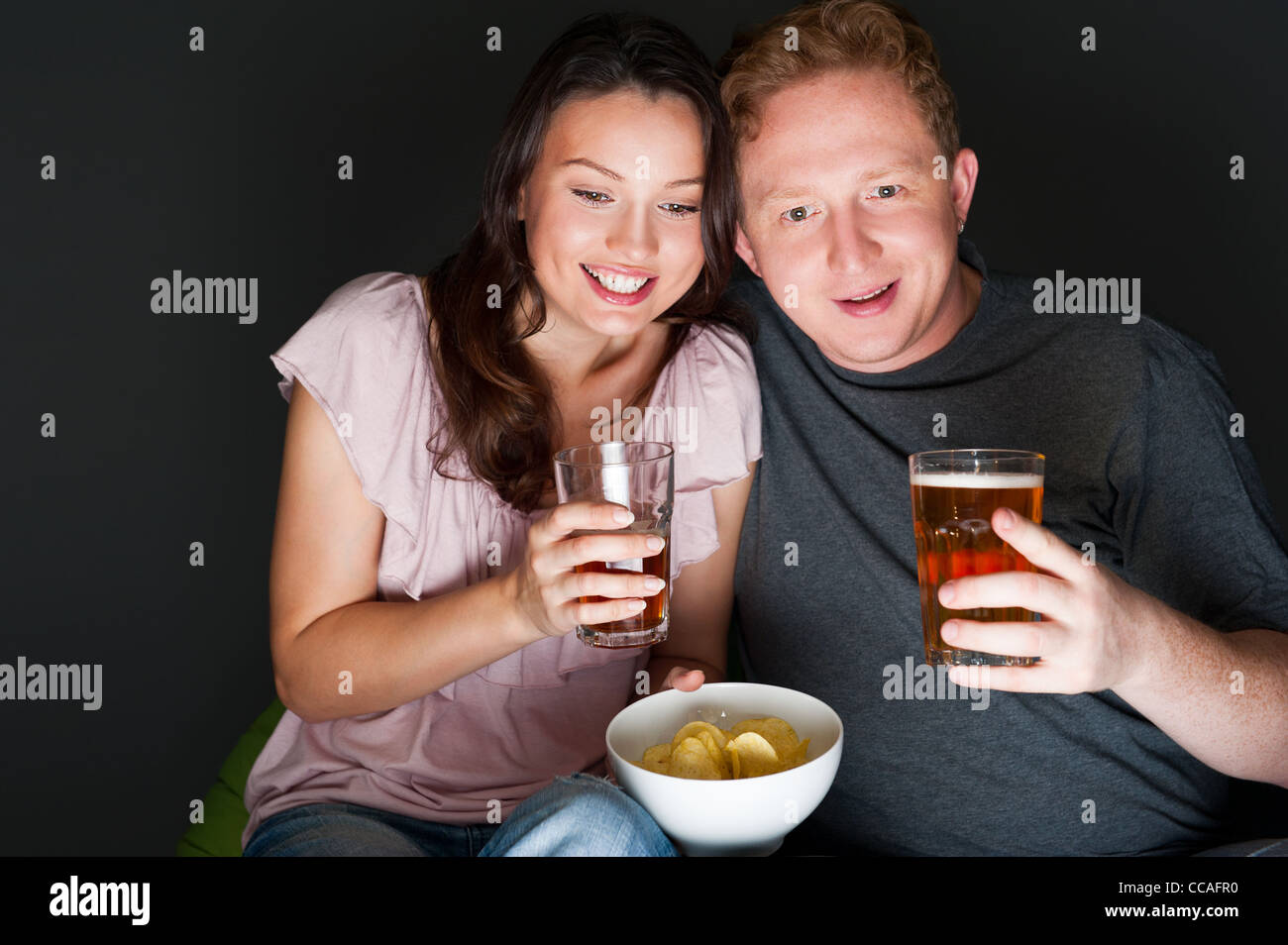 Happy couple sitting together watching something intresting on ...