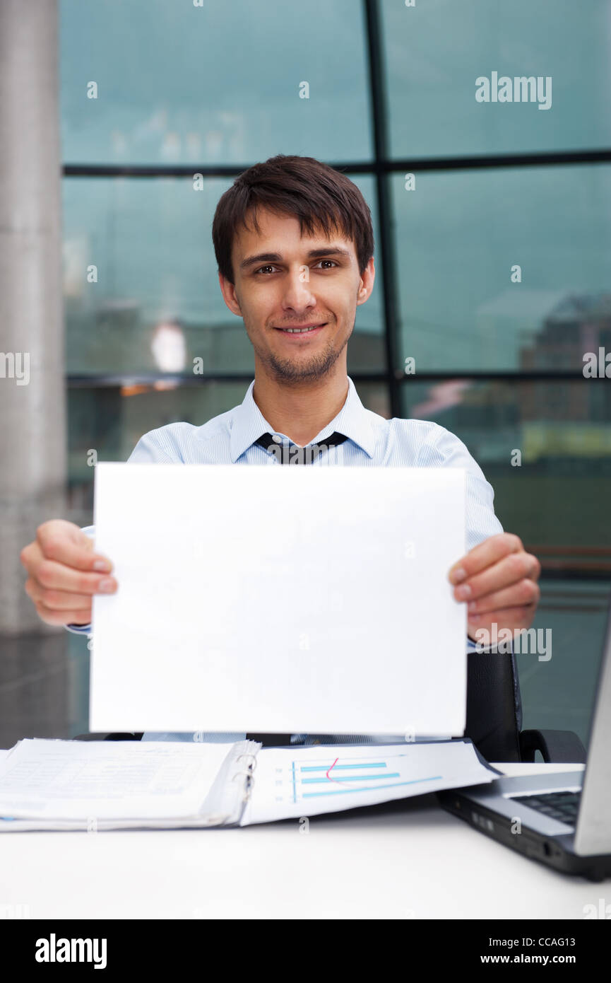 Attractive man in business suit with blank sign sitting at his office ...