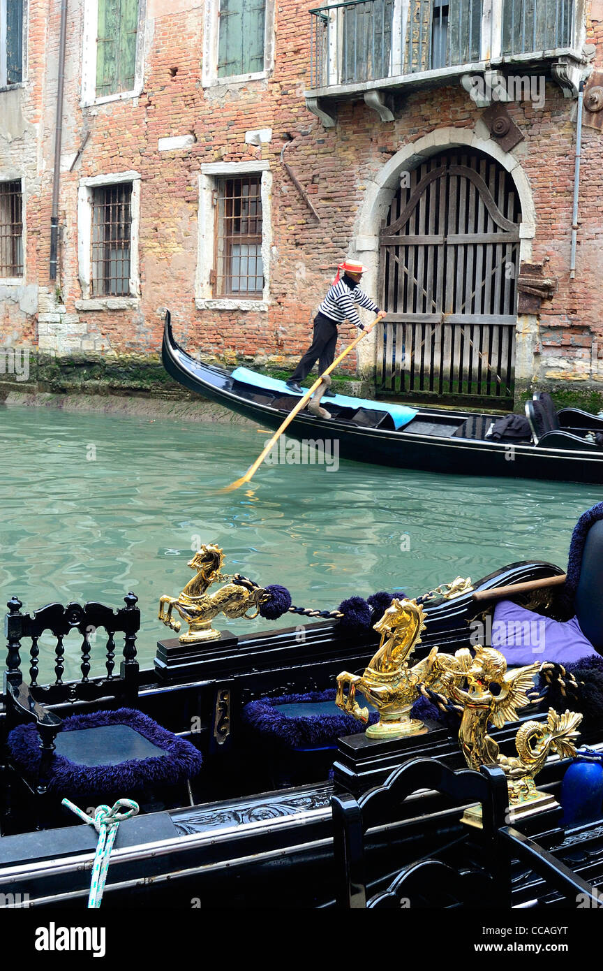 Gondolier propelling his boat past another Gondola in an old canal ...