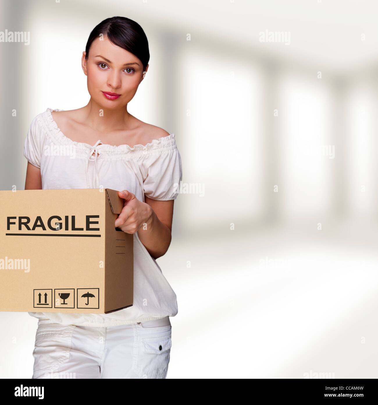 A woman holding a box inside office building or home interior. Package ...