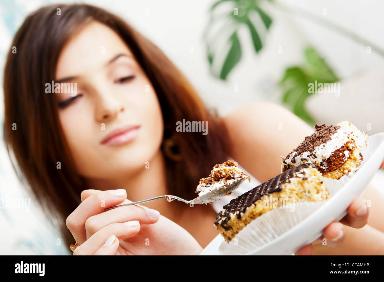Young beautiful woman with a cake. Closeup Portrait. Sitting on sofa at ...
