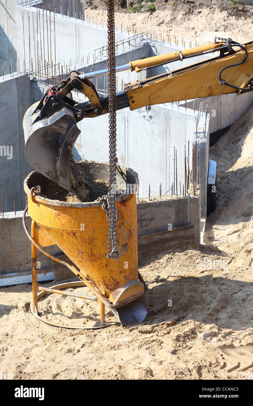 digger, excavator construction building site pouring concrete in form ...