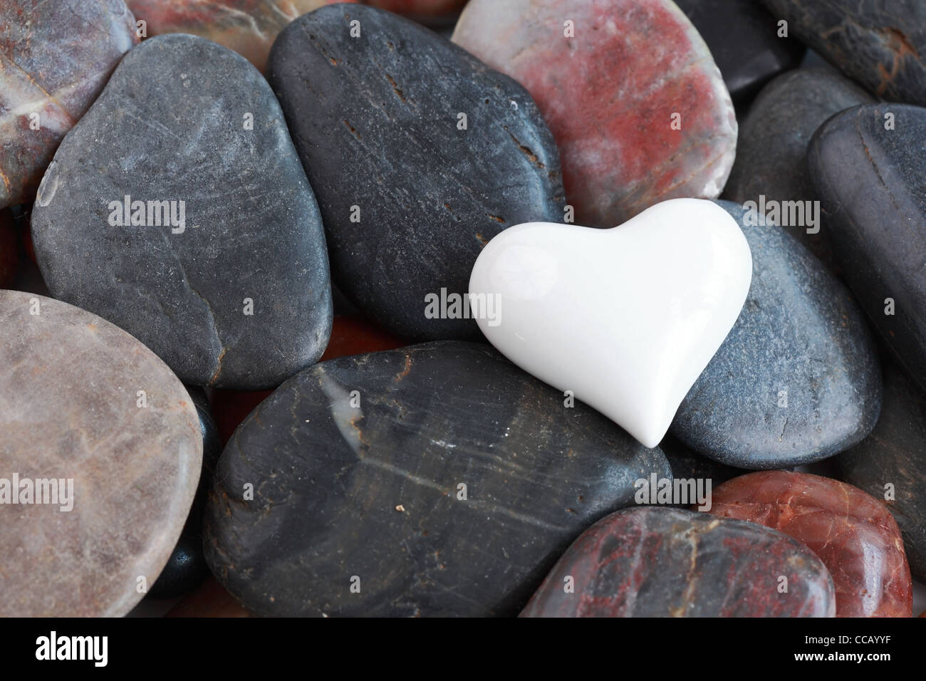 White heart heart surrounded by natural stones Stock Photo - Alamy