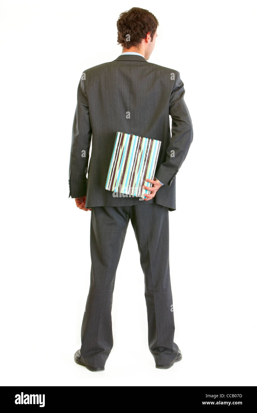 Modern businessman hiding present behind his back and standing back to ...