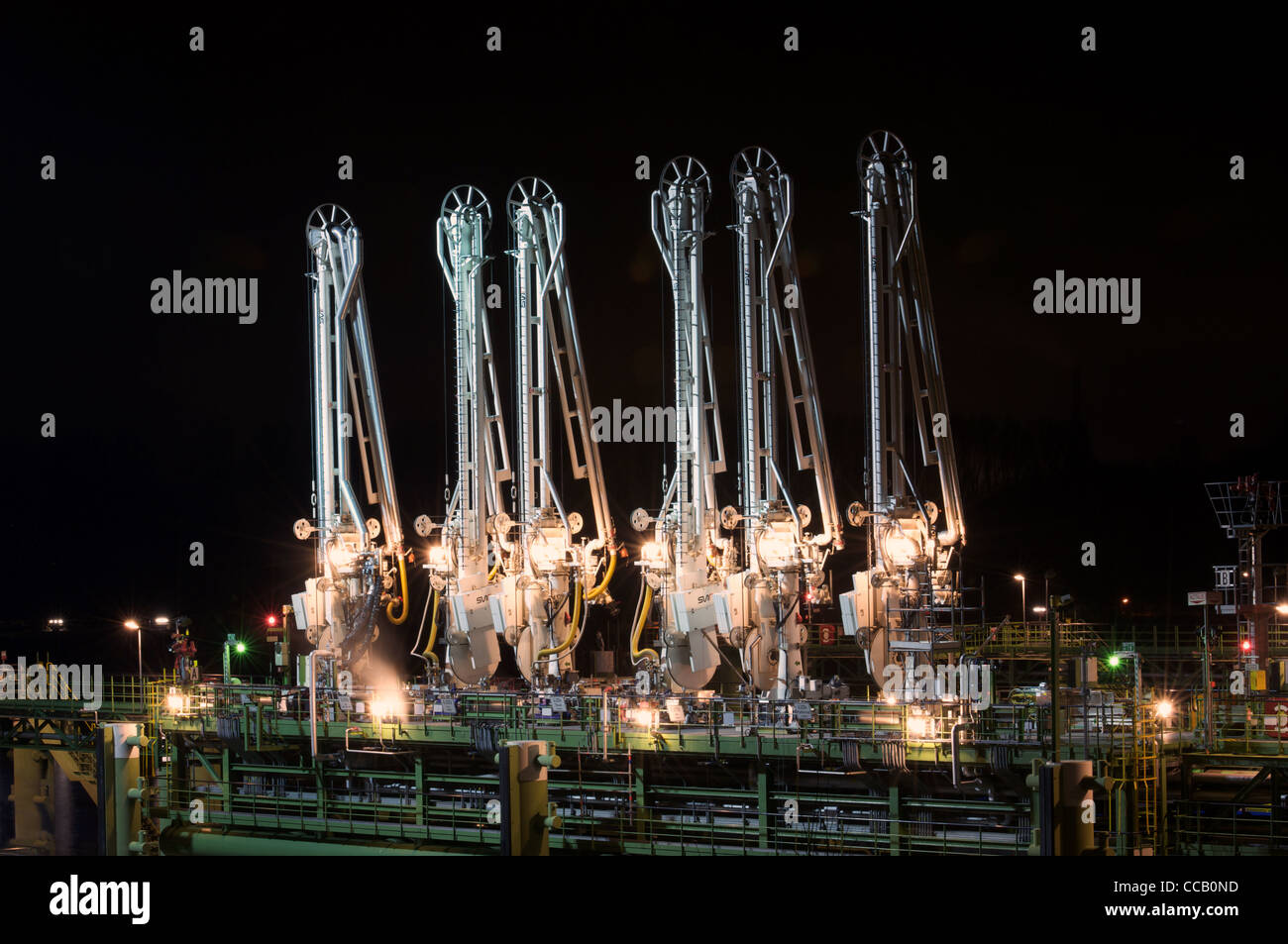 Booms used to transfer oil to barges at an oil refinery beside the ...