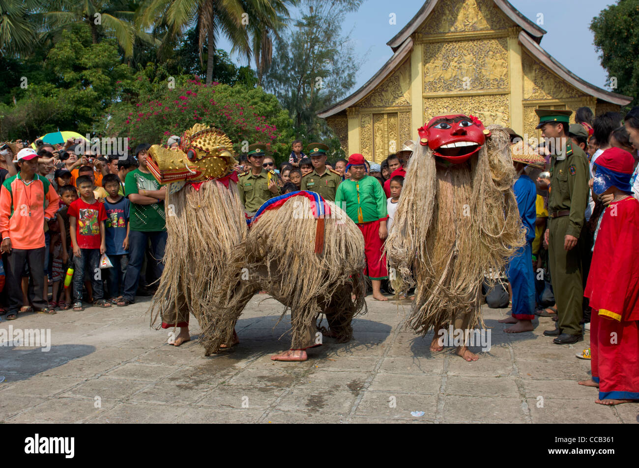 Mythical masked figures dancing in front of golden Sim at Wat Xieng ...