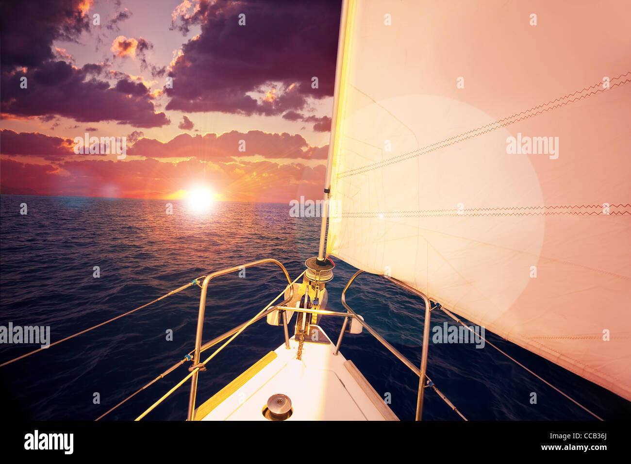 Romantic sunset and sail boat, dramatic sky with purple clouds and sun ...