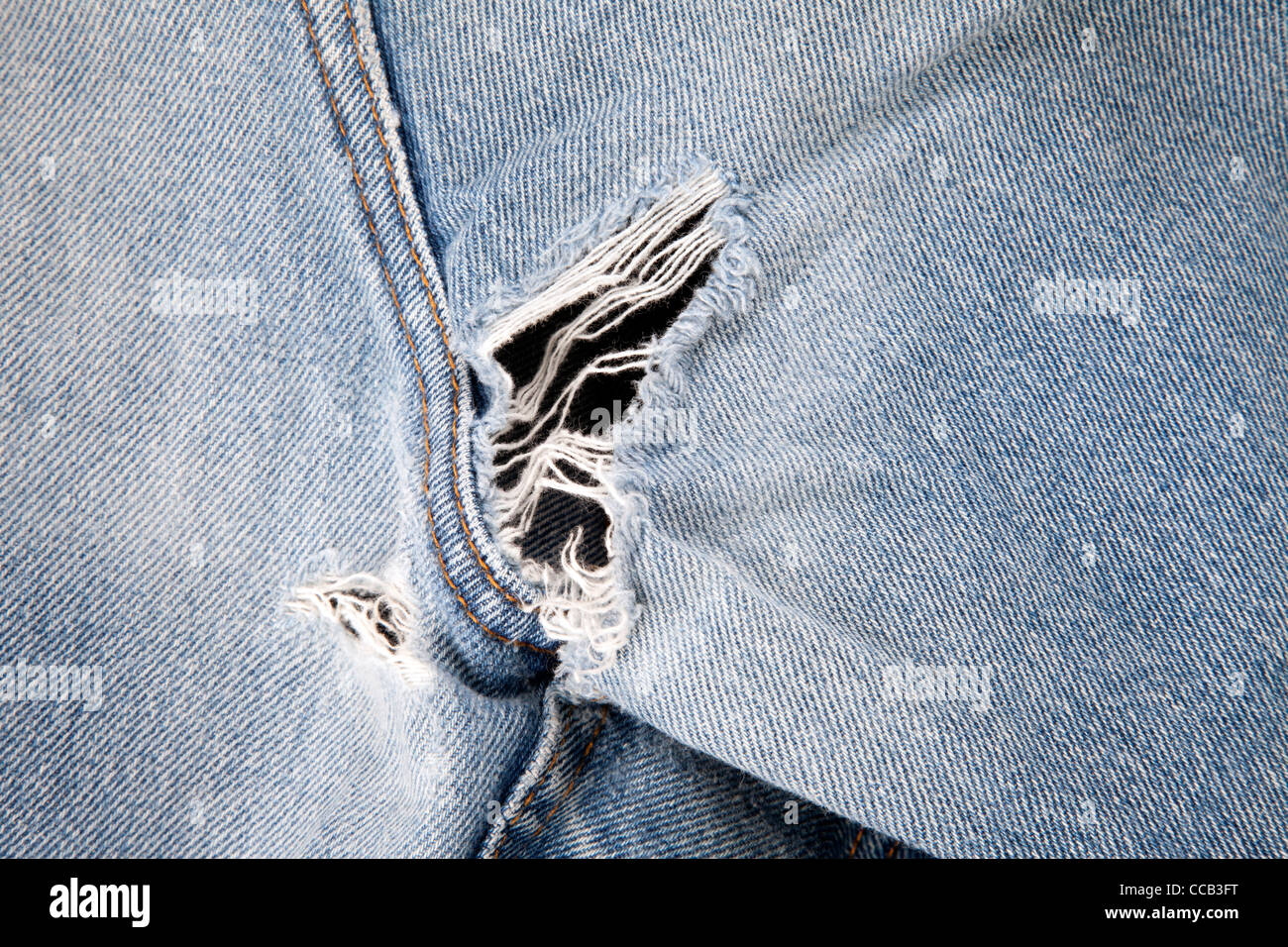 Close up of hole in an old pair of blue jeans showing the frayed ...