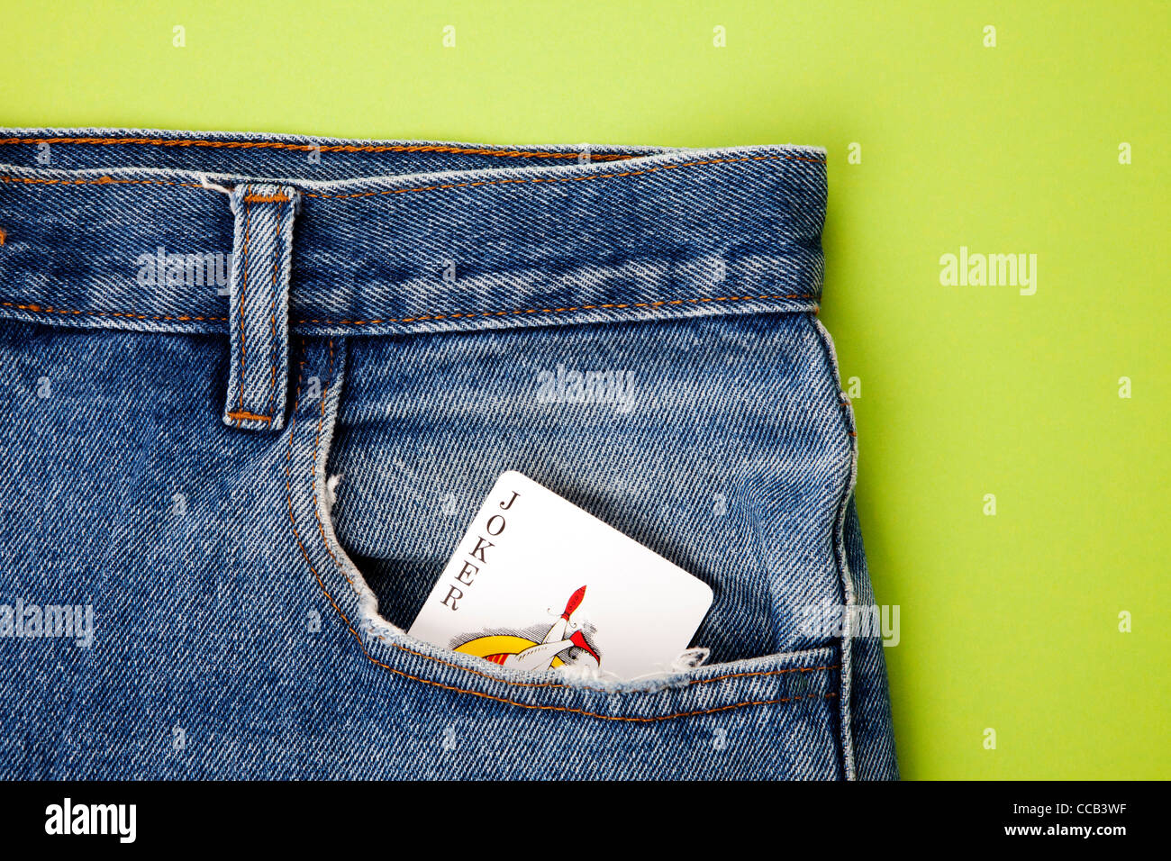 Joker playing card in blue jeans pocket with green background Stock ...