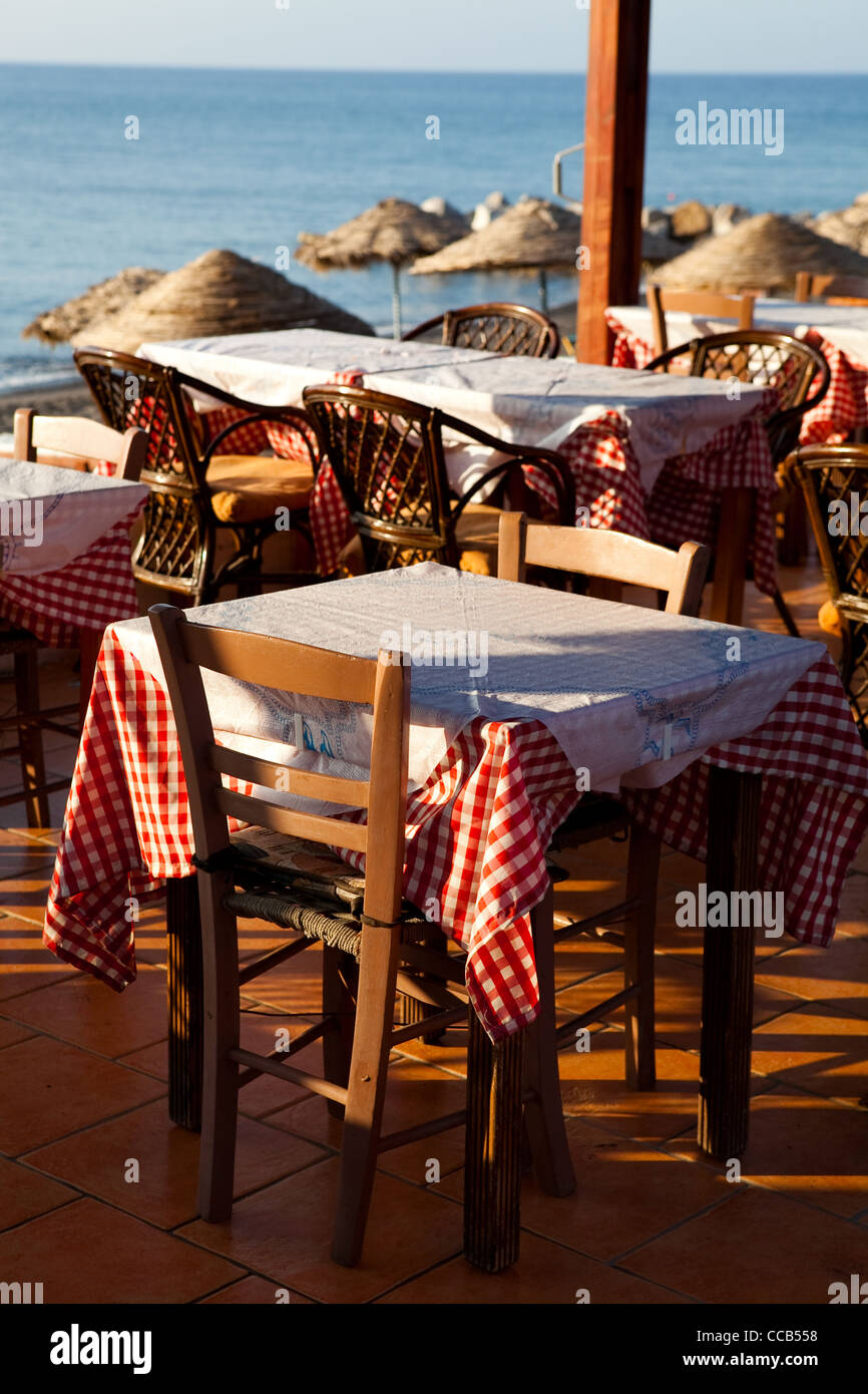 Outdoor restaurant tables by the beach in Perissa, Santorini, Greece ...