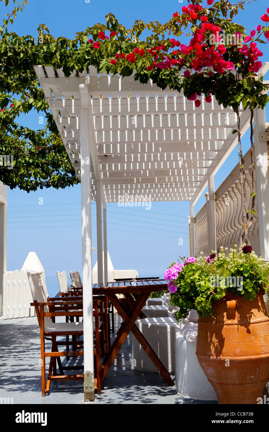 Terrace setting with tables, chairs and flowers in Thira, Santorini ...
