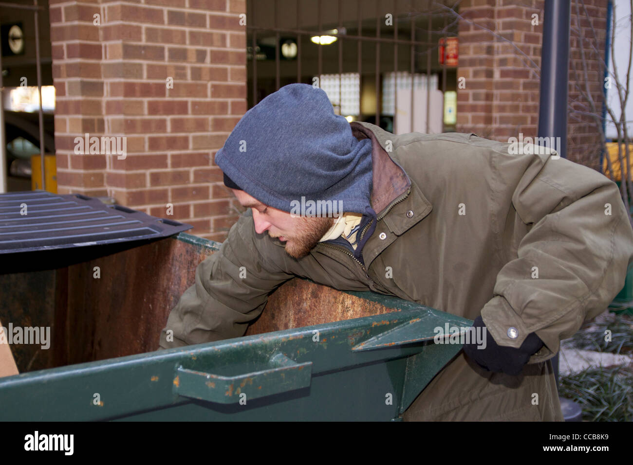 Homeless man looking into garbage dumpster Stock Photo - Alamy