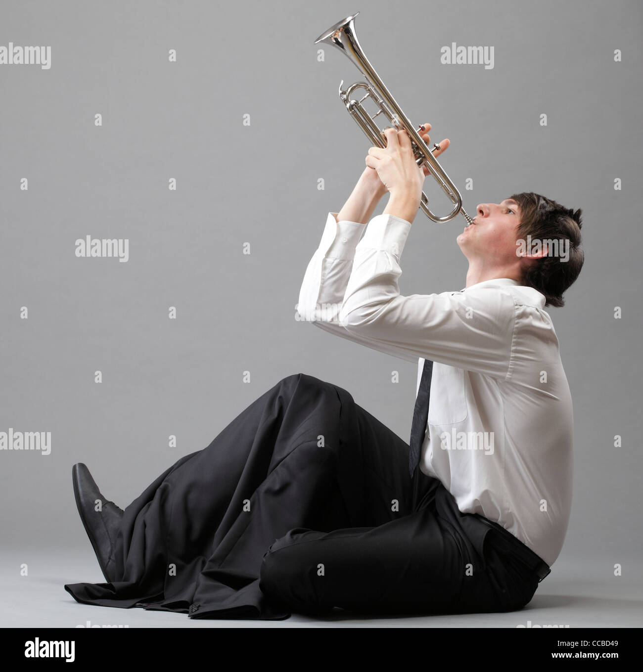 Portrait of a young jazz man playing his Trumpet grey background Stock ...