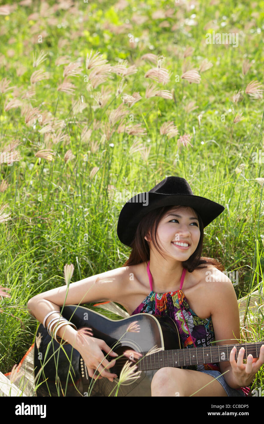 smiling woman playing guitar outside on the grass Stock Photo - Alamy