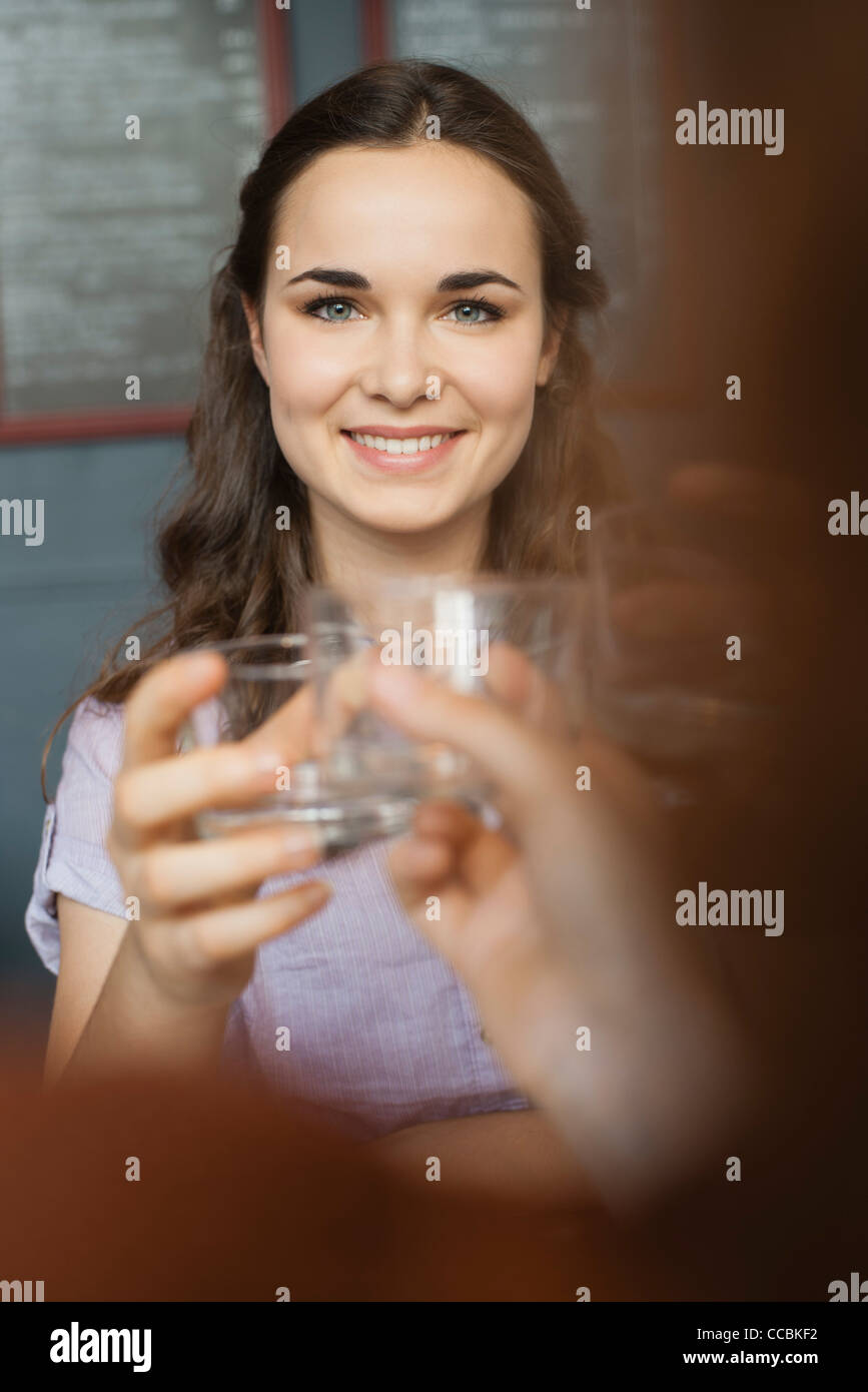 Young woman raising glass with friend Stock Photo - Alamy