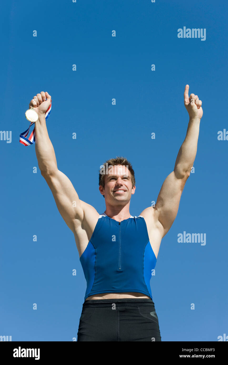 Male athlete holding up gold medal Stock Photo - Alamy