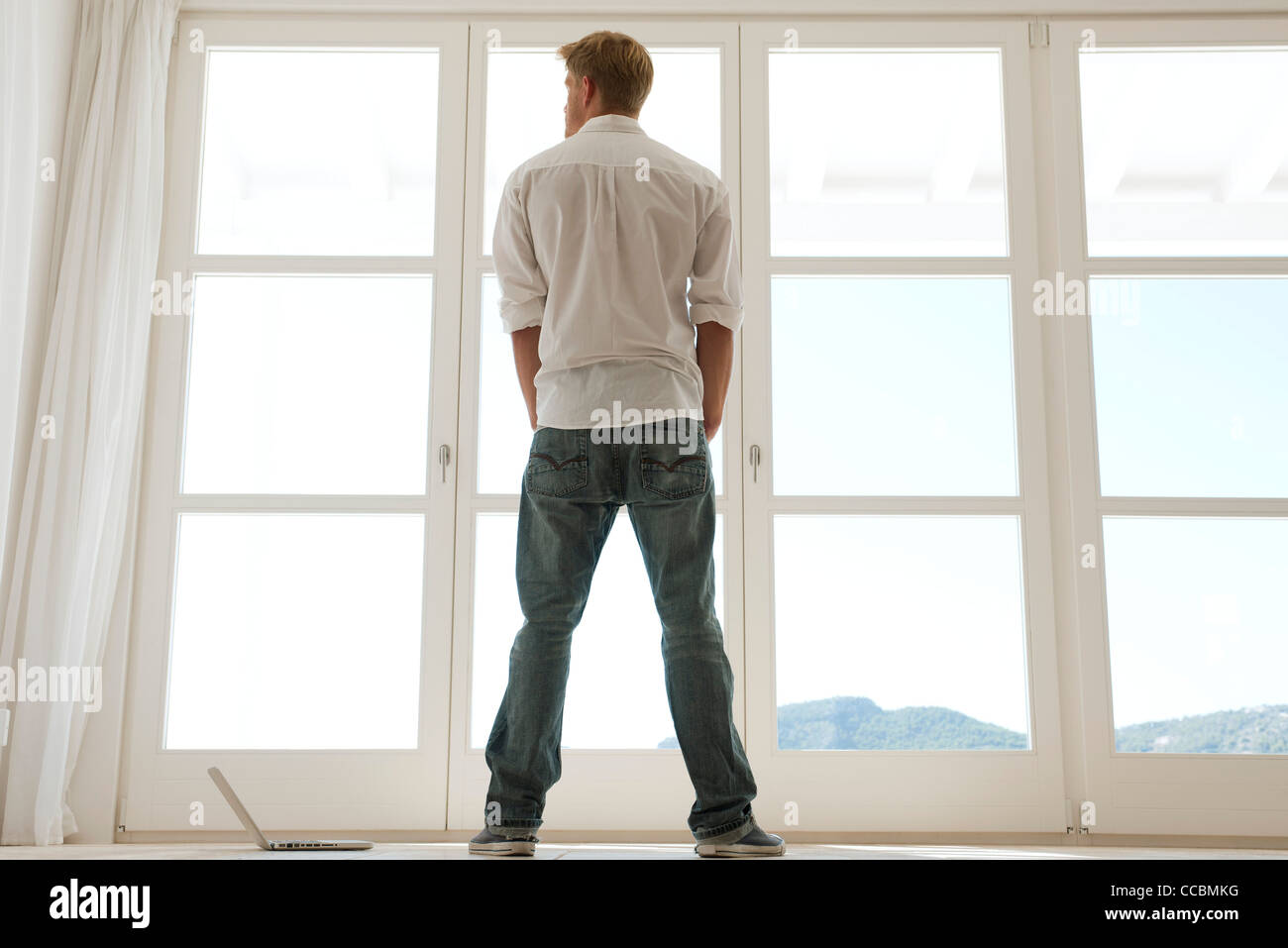 Man looking out window, rear view Stock Photo - Alamy