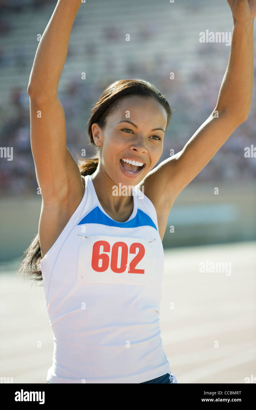 Woman running on track with arms raised in victory Stock Photo - Alamy
