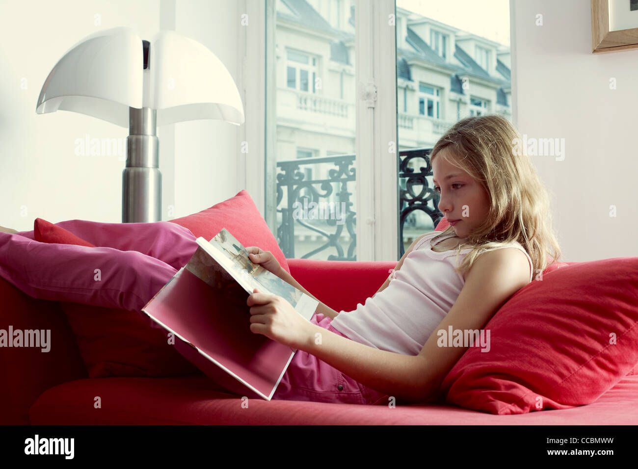 Girl relaxing on couch reading book Stock Photo - Alamy