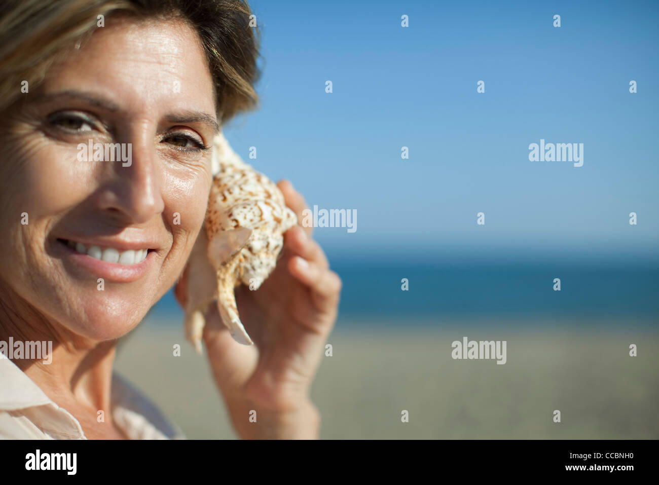 Woman listening to seashell, portrait Stock Photo - Alamy