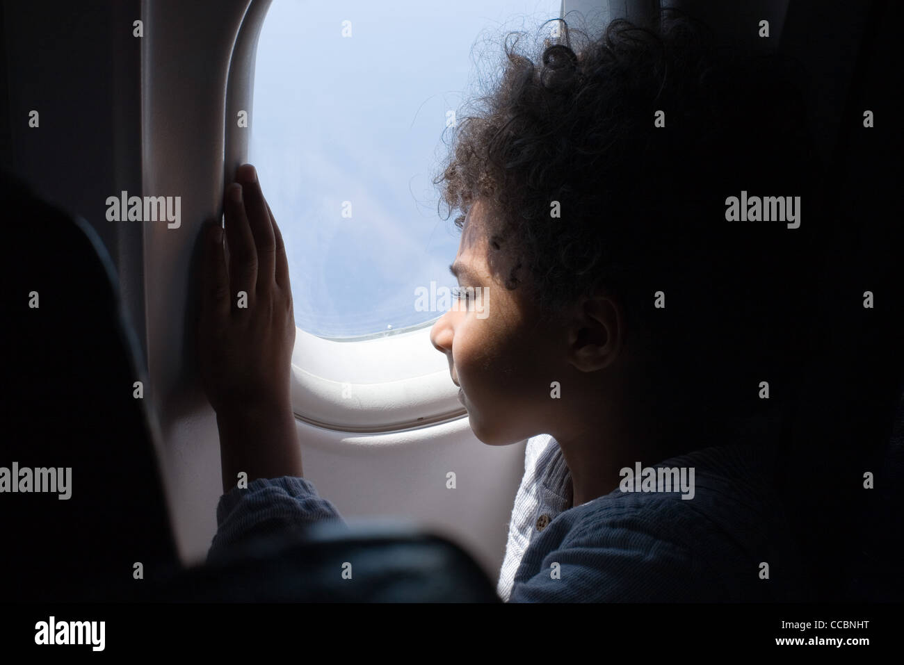 Boy looking out airplane window Stock Photo - Alamy