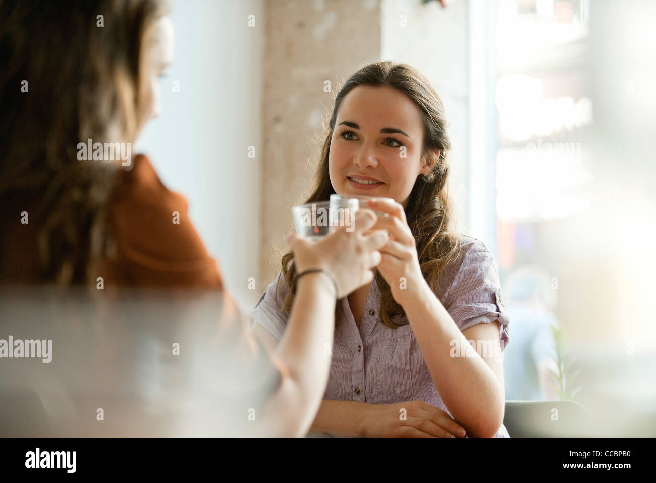 Young women raising glasses Stock Photo - Alamy