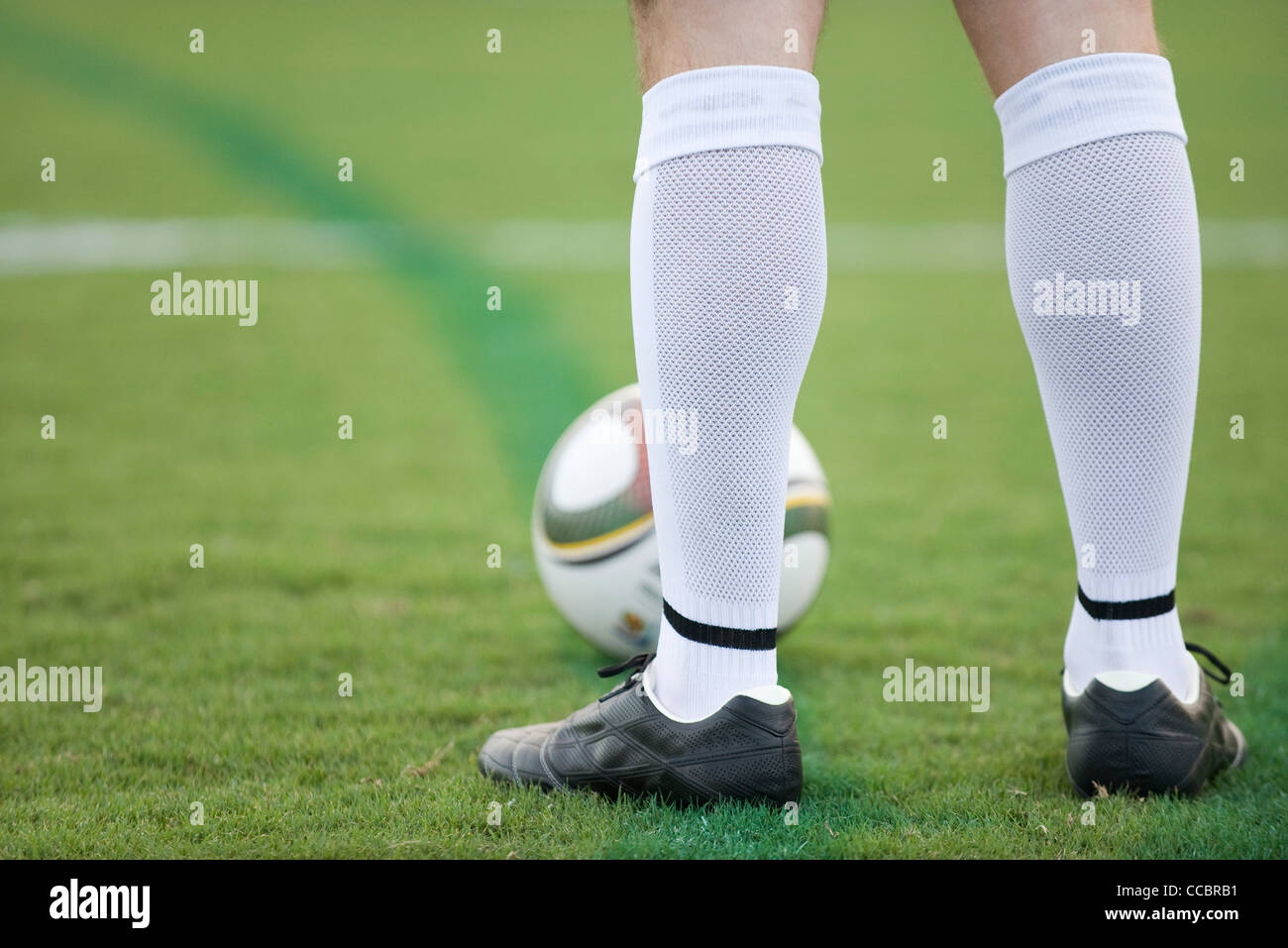 Soccer player standing on field, low section Stock Photo - Alamy