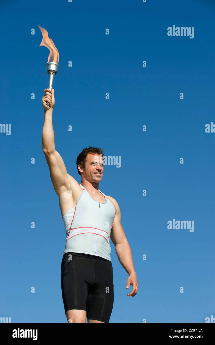 Male athlete holding up torch Stock Photo - Alamy