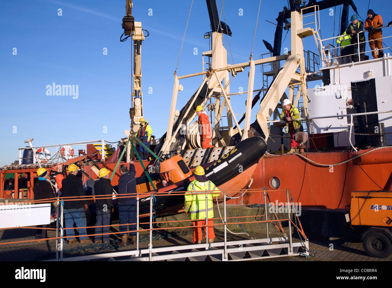 Men loading inflatable boat North Sea offshore supply vessel, Great ...