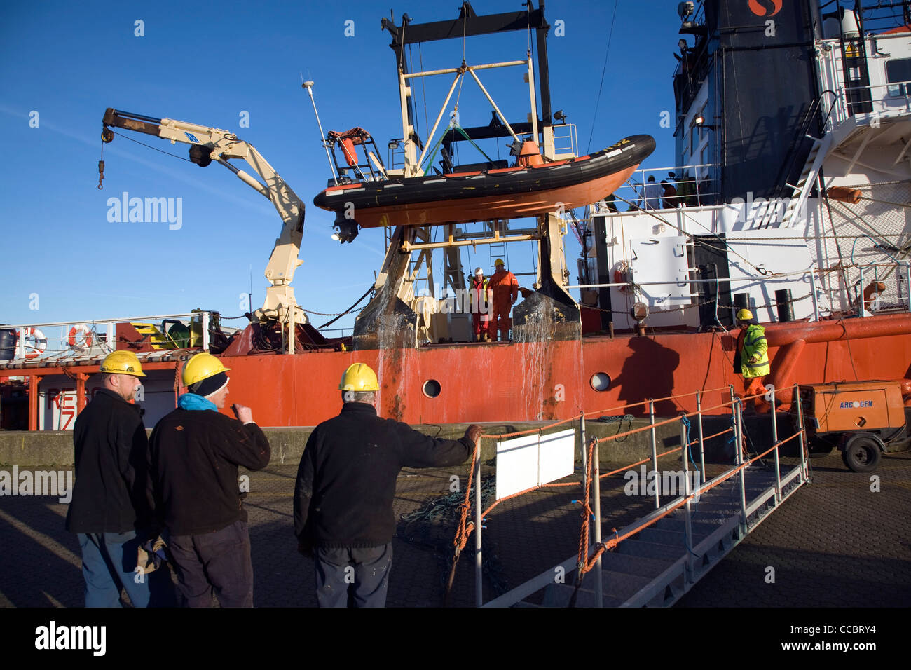 Men loading inflatable boat North Sea offshore supply vessel, Great ...