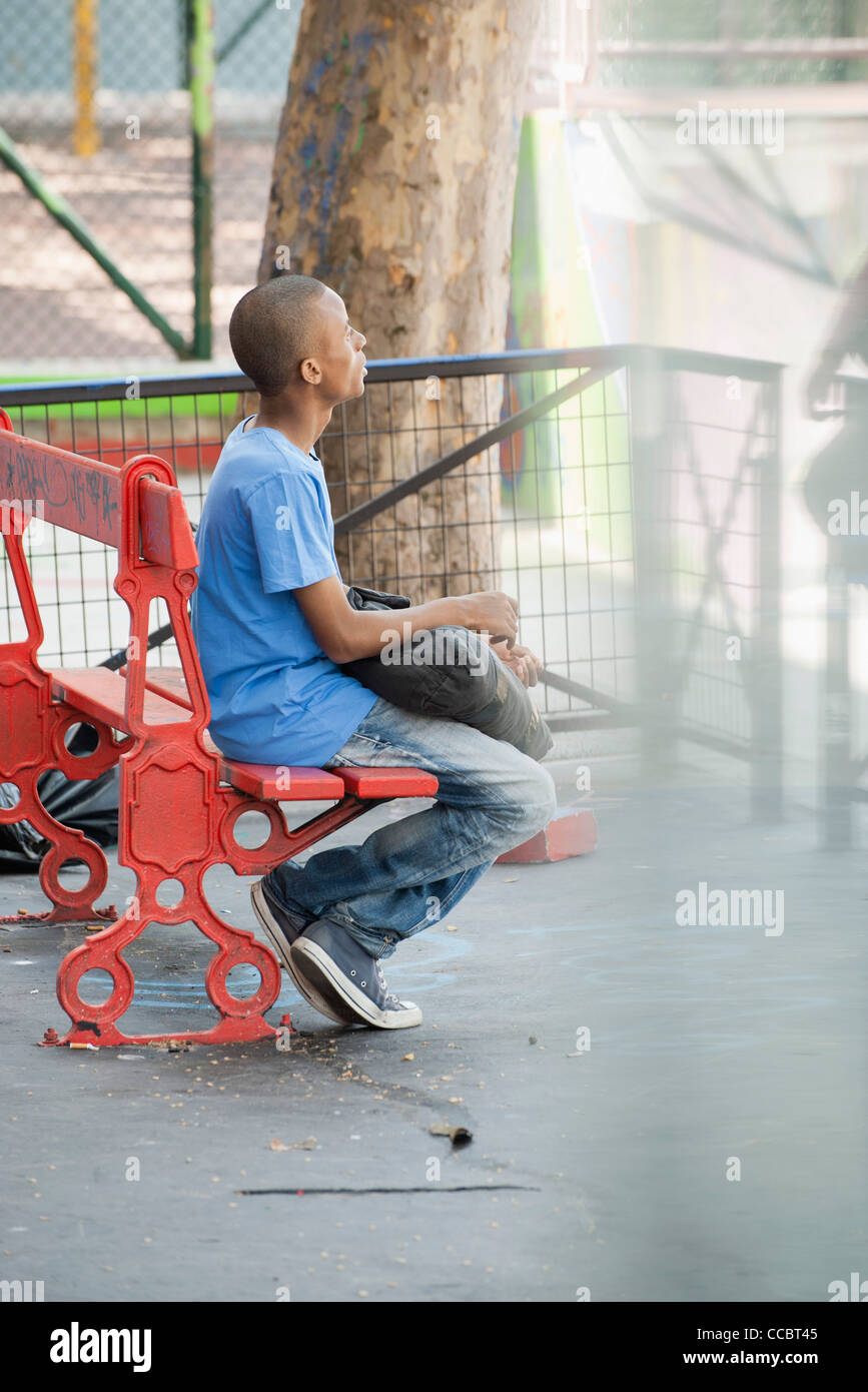 Young man sitting on bench Stock Photo - Alamy
